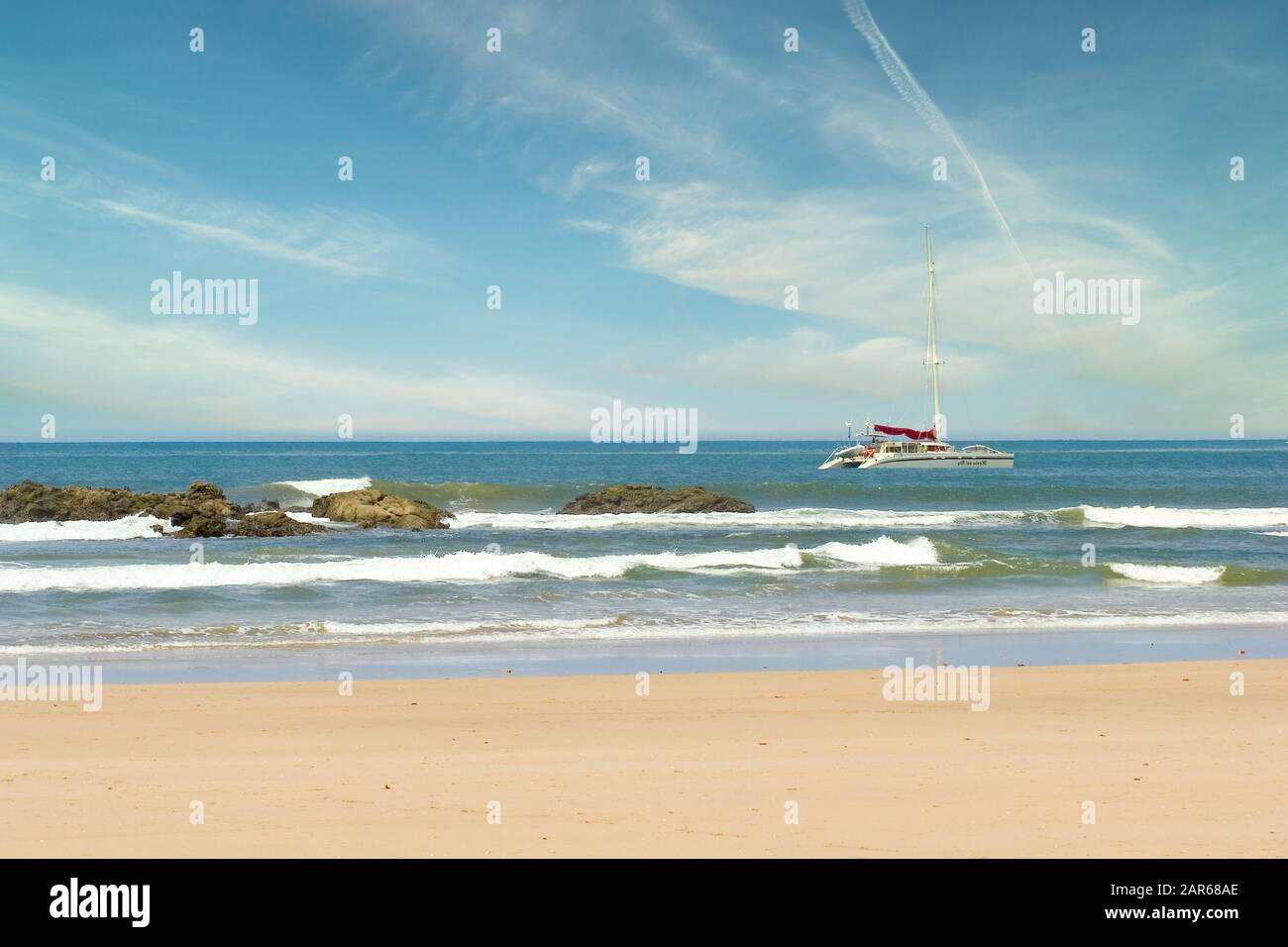 Catamaran Past Rocks Stock Photo - Alamy