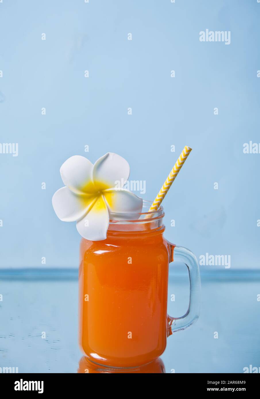 Glass of tropical exotic multifruit juice cocktail drink with Plumeria ...