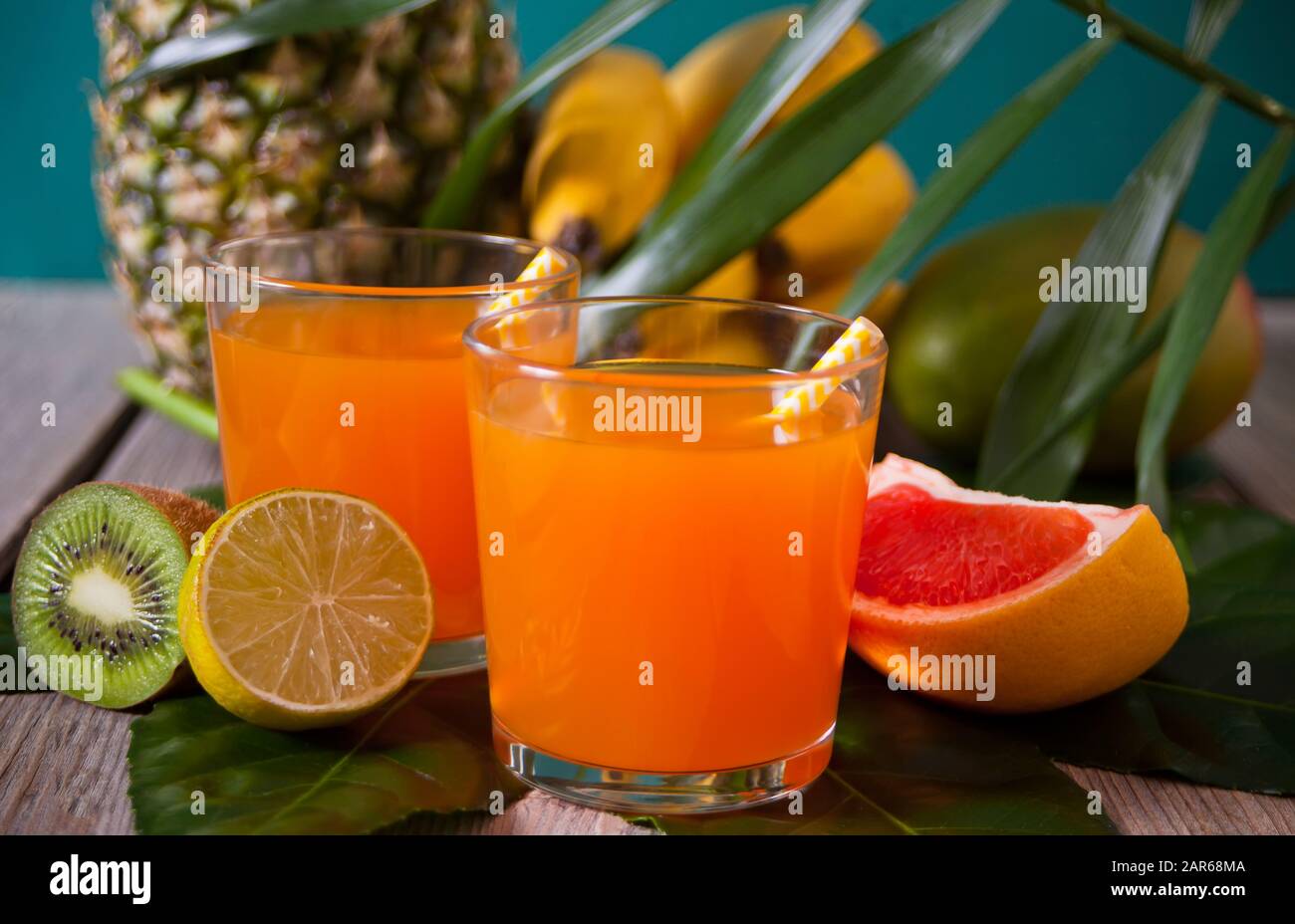 Two glasses of tropical exotic multifruit juice under a palm leaves ...