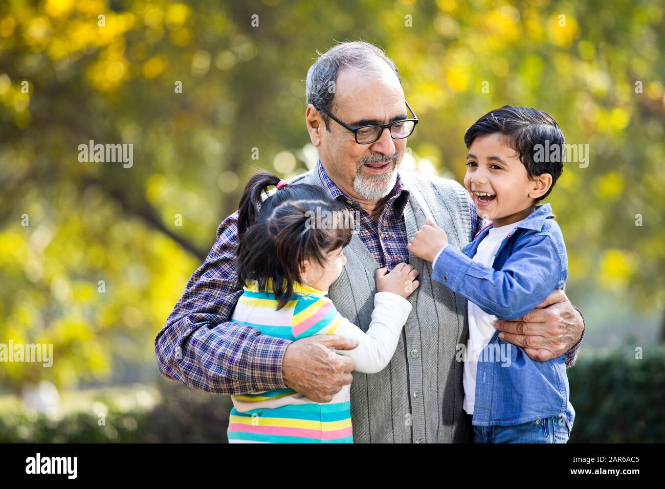 Grandchildren having fun with grandfather at park Stock Photo - Alamy