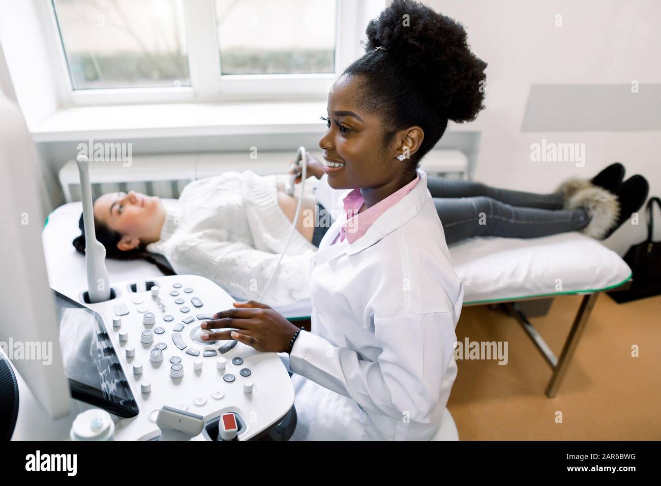 Smiling African woman doctor general practitioner is checking female ...