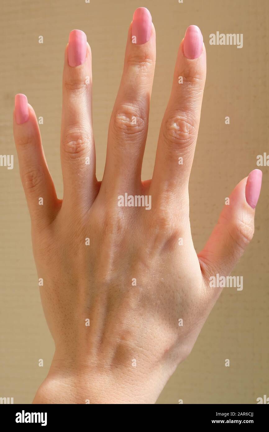 Female hand on a yellow background. Fingers with pink polish and long ...