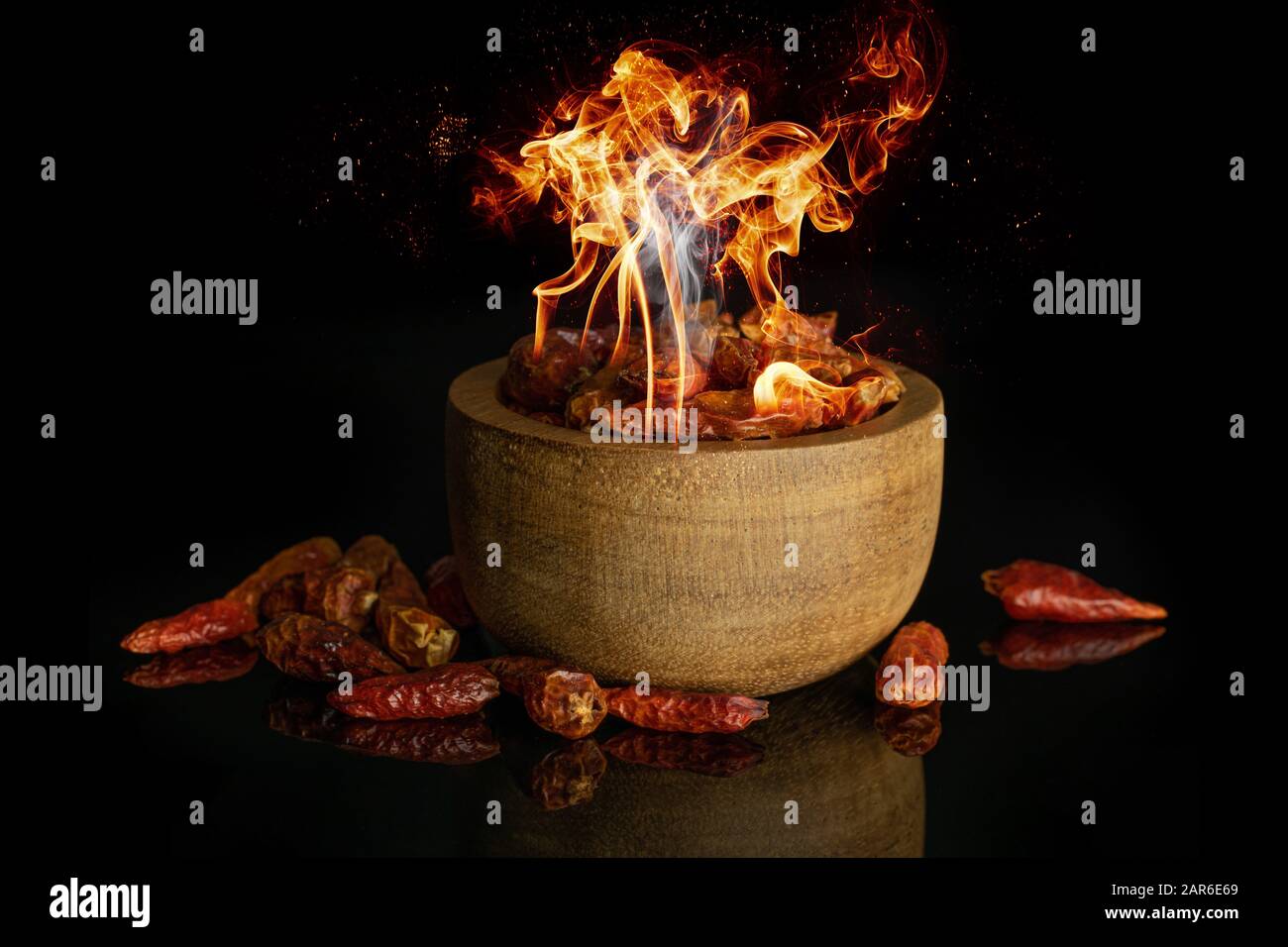 Lot of small hot peppers with burning fire in wooden bowl isolated on ...