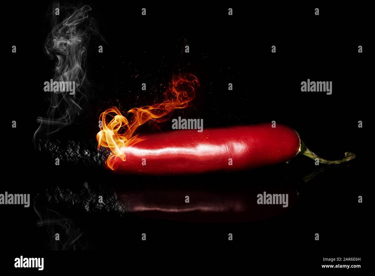 One charred hot red chili burning fire isolated on black glass Stock ...