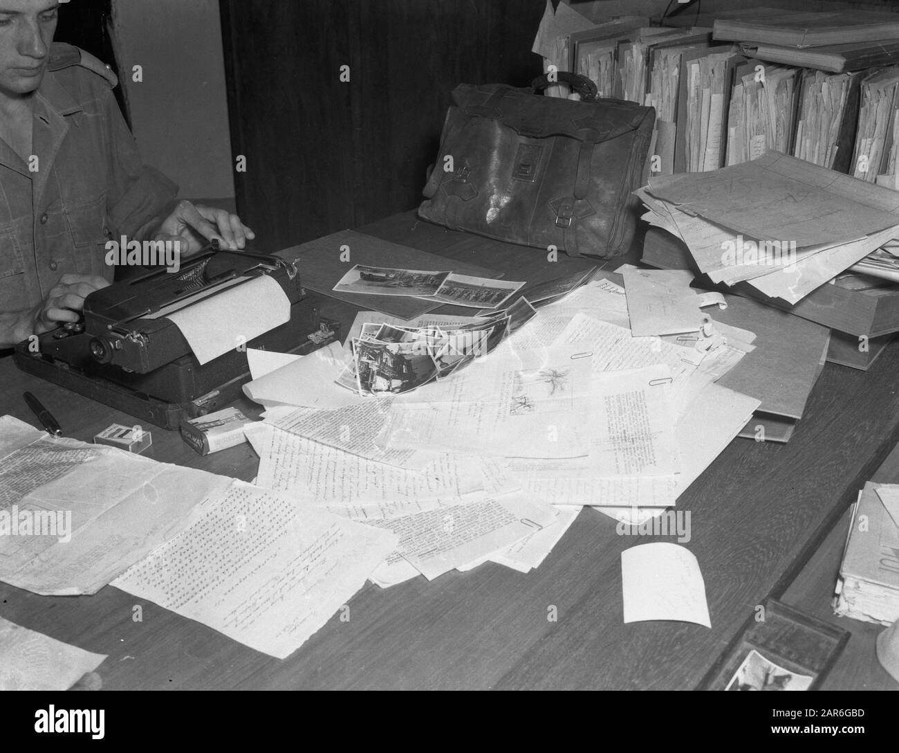 Military behind typewriter. In front of him are several letters ...