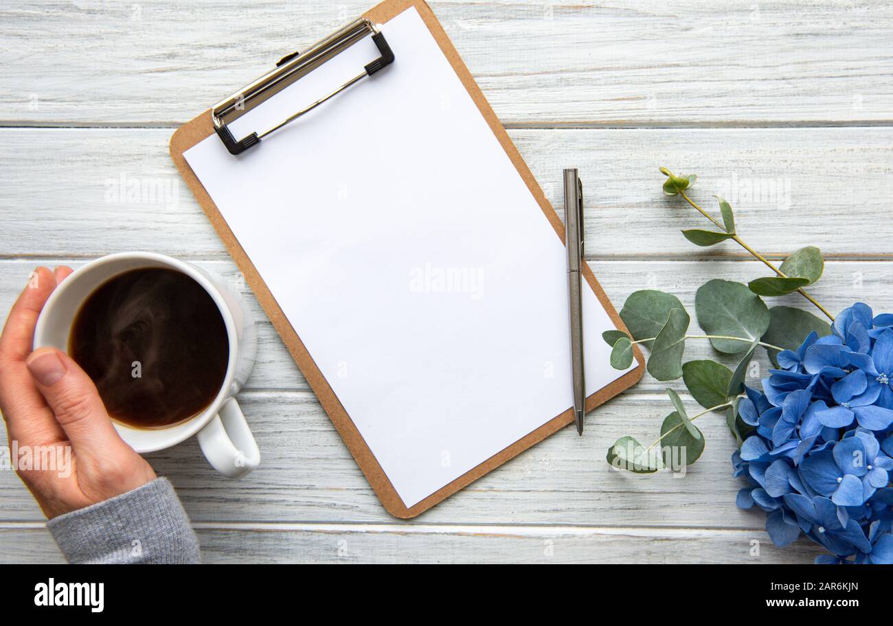 Home office desk workspace with blank paper clipboard, blue hydrangea ...