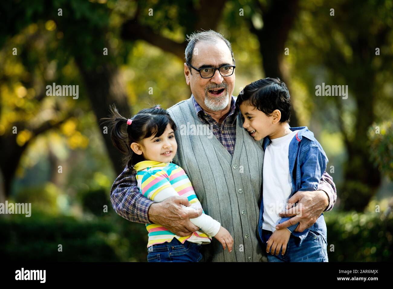 Grandchildren having fun with grandfather at park Stock Photo - Alamy