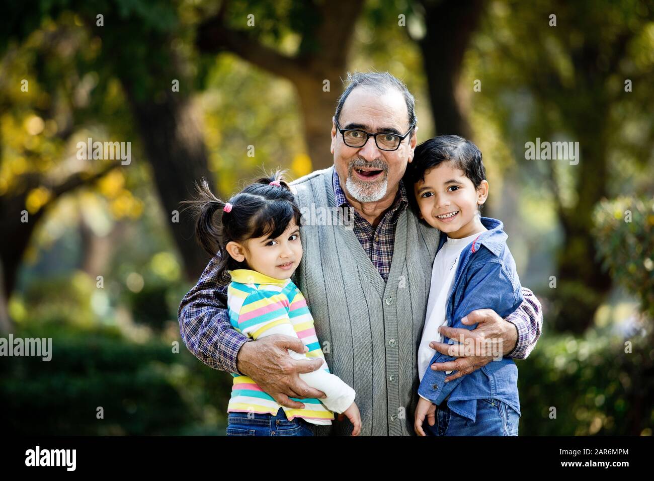 Grandchildren having fun with grandfather at park Stock Photo - Alamy