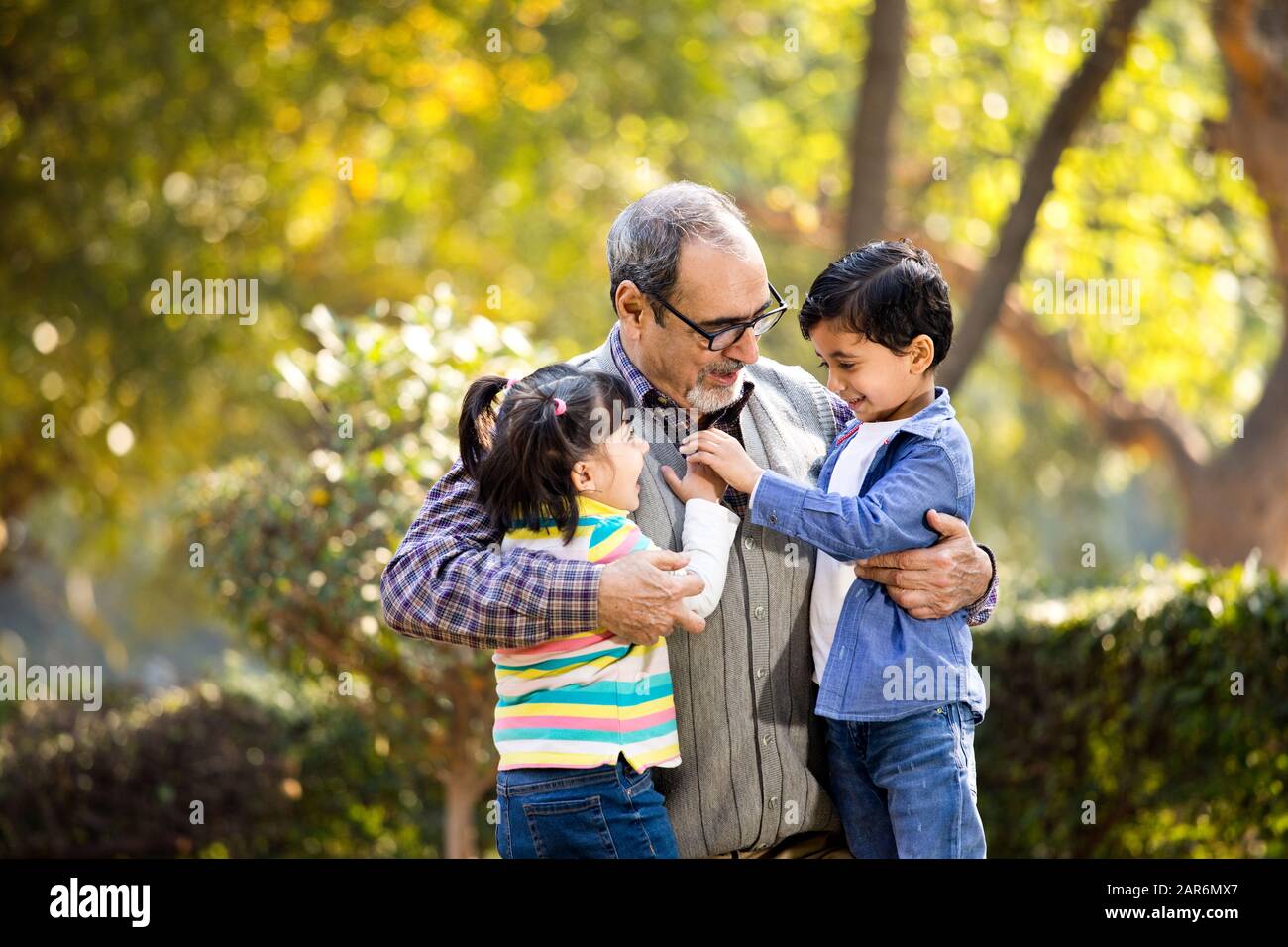 Grandchildren having fun with grandfather at park Stock Photo - Alamy