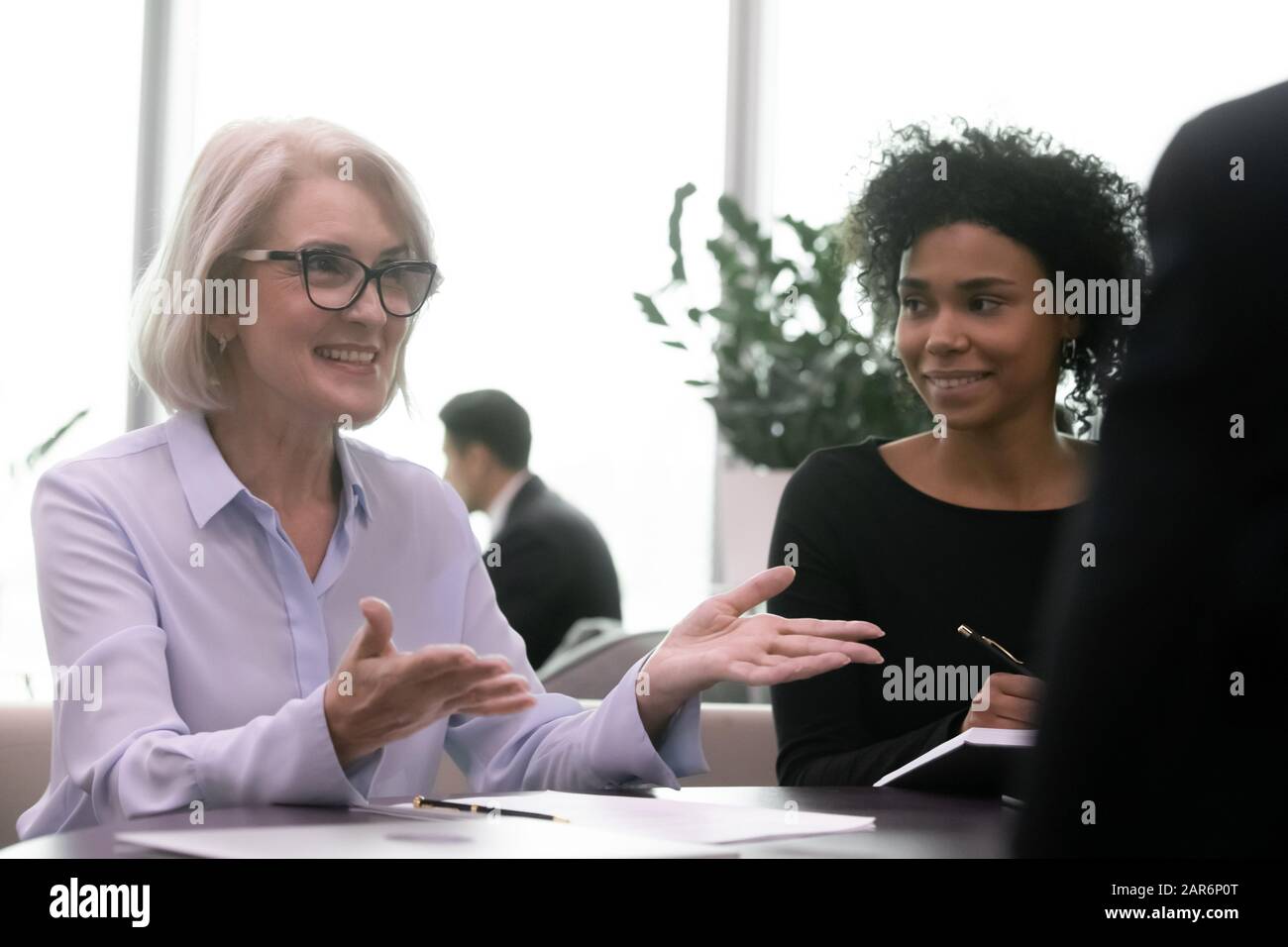 Middle aged female boss in eyeglasses conducting meeting with partners ...