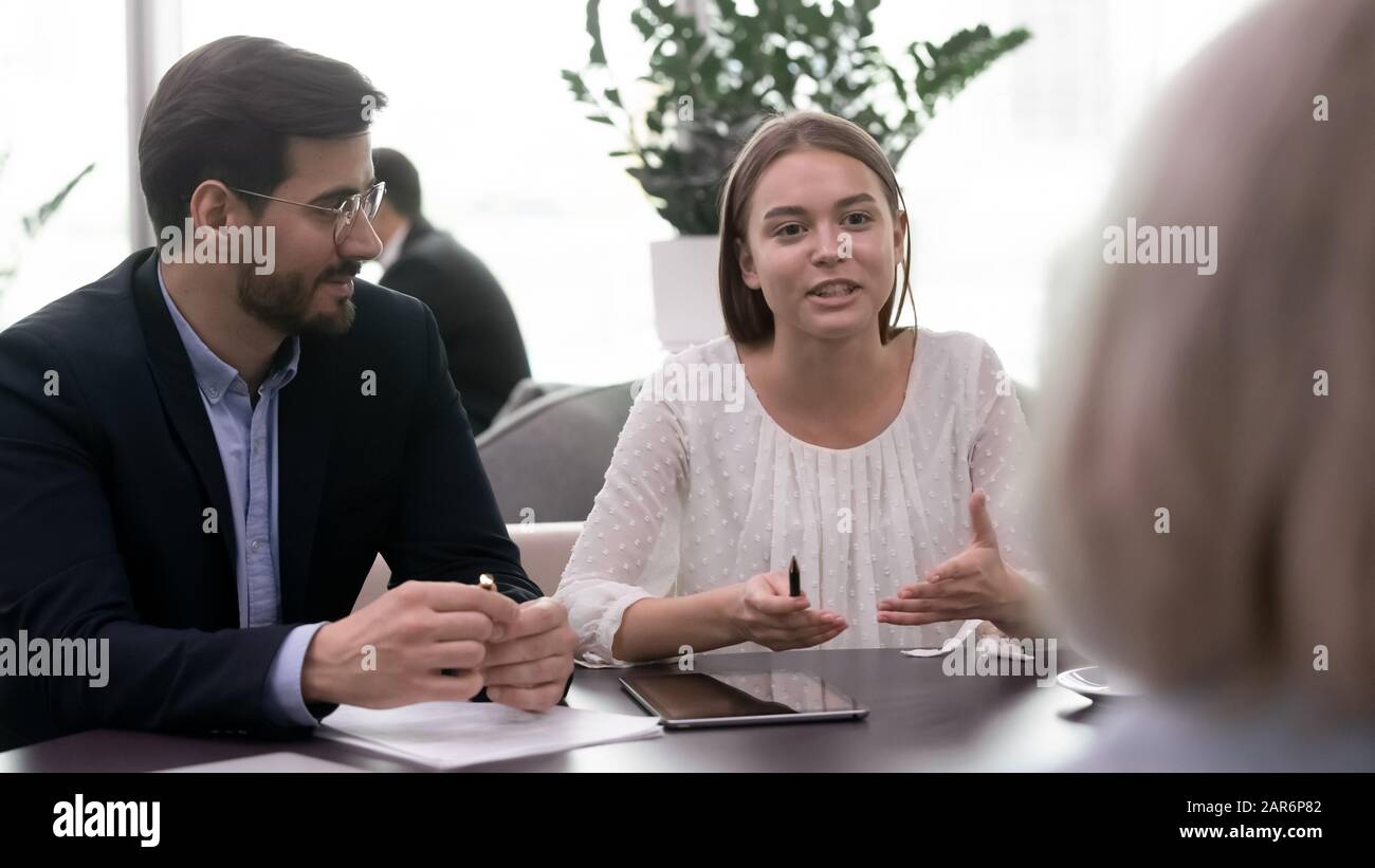Young confident female manager asking questions explaining project ...