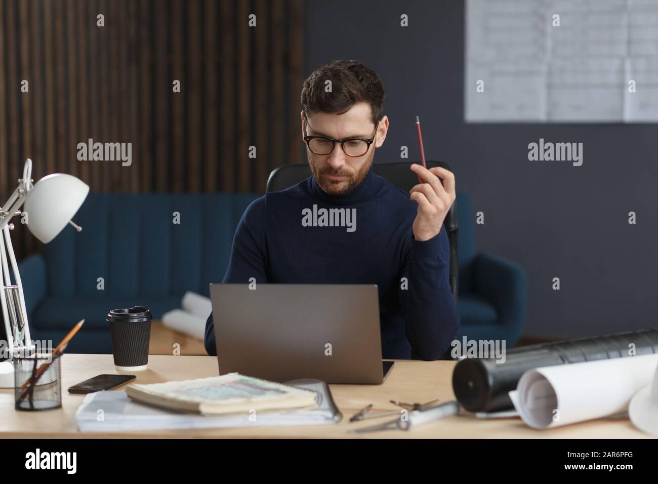 Architect working in office with laptop.Engineer thinks over ...