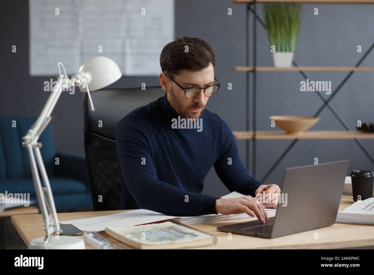 Architect working in office with laptop. Engineer thinks over ...