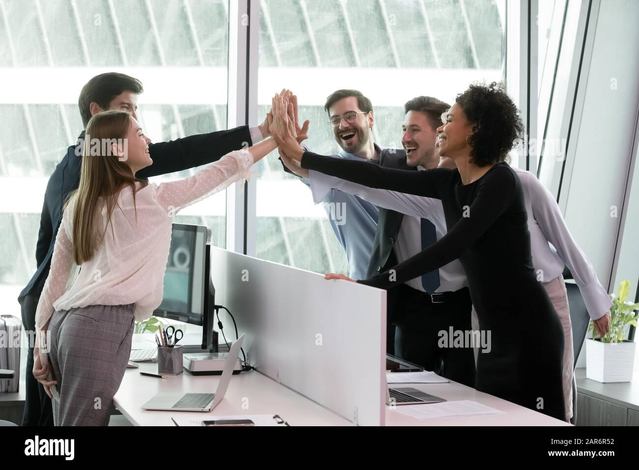 Overjoyed diverse employees giving high five, celebrating successful ...