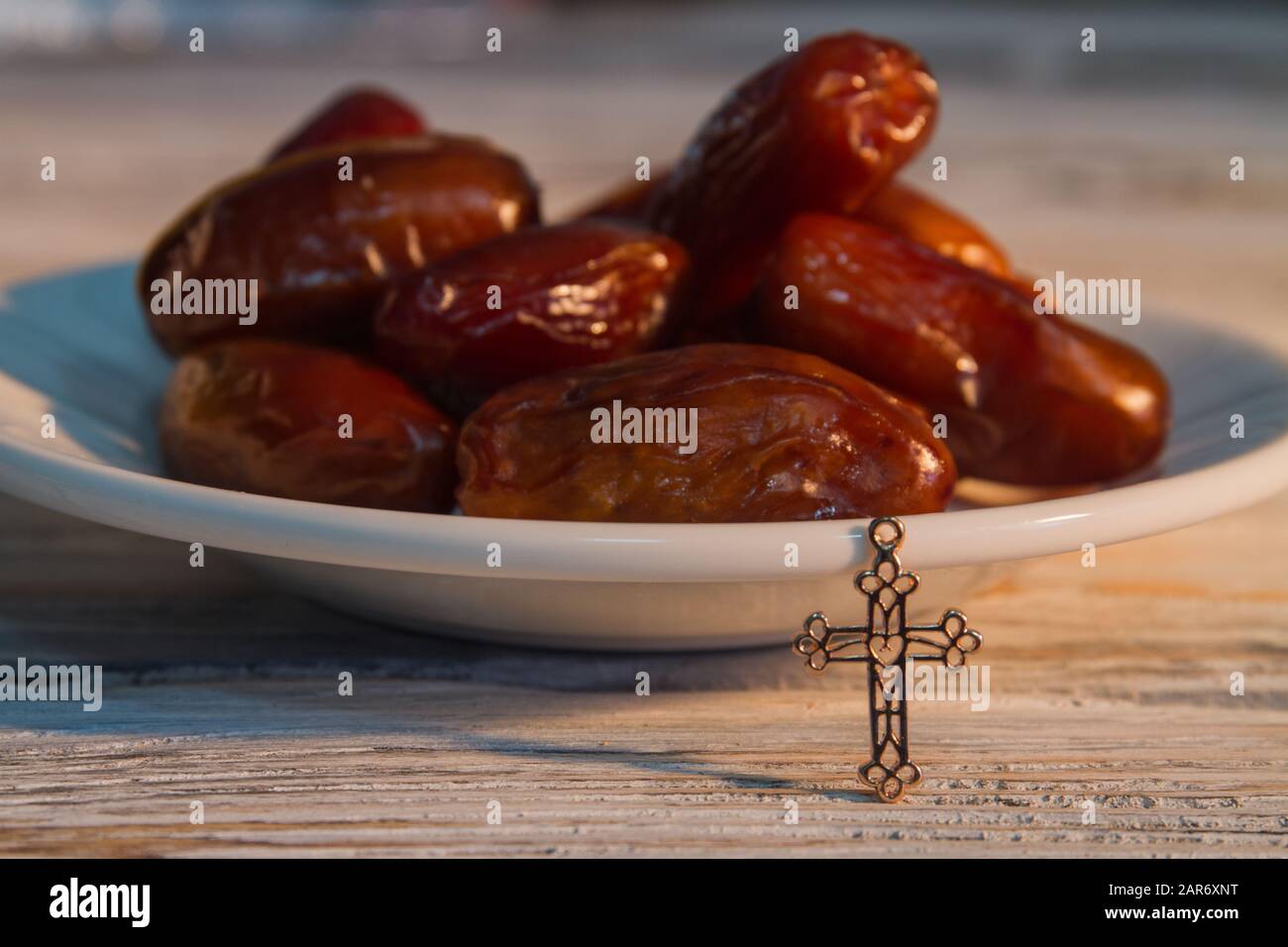 Plate of date fruits and small golden cross Stock Photo - Alamy