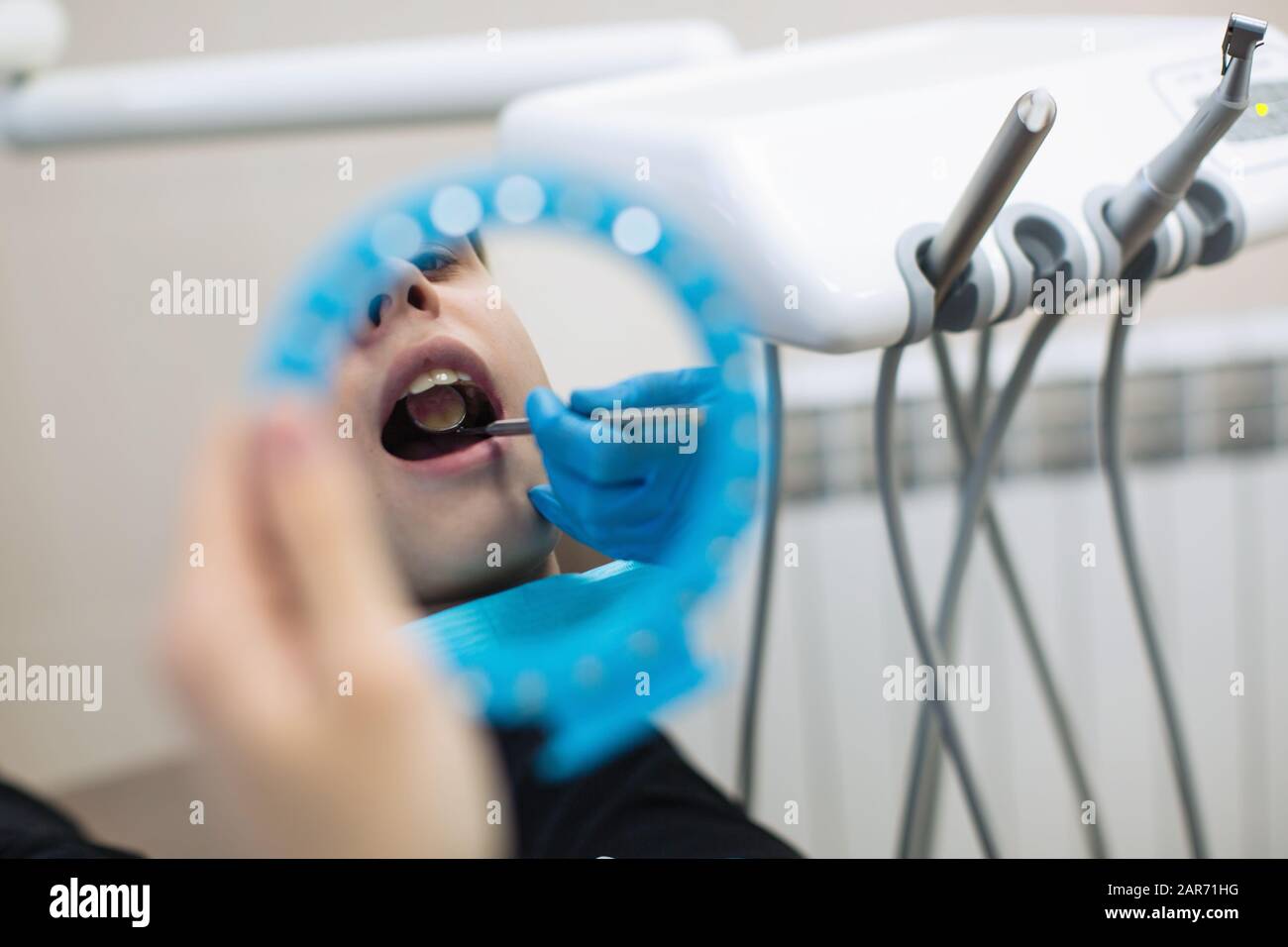 Reflection in the mirror mouth and teeth checkup of guy in a dental ...