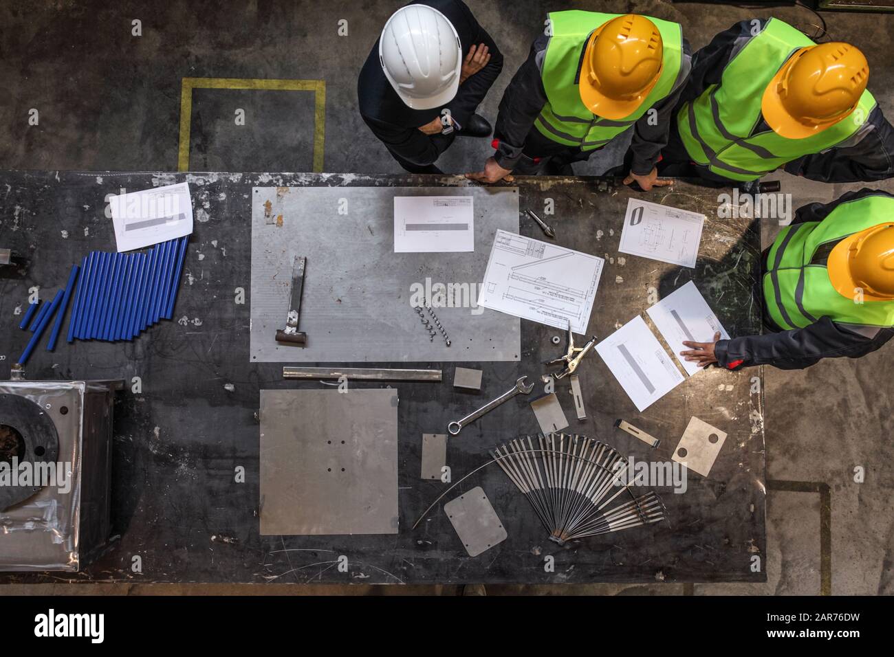 Team of workers and foreman look at documents and blueprints on table ...