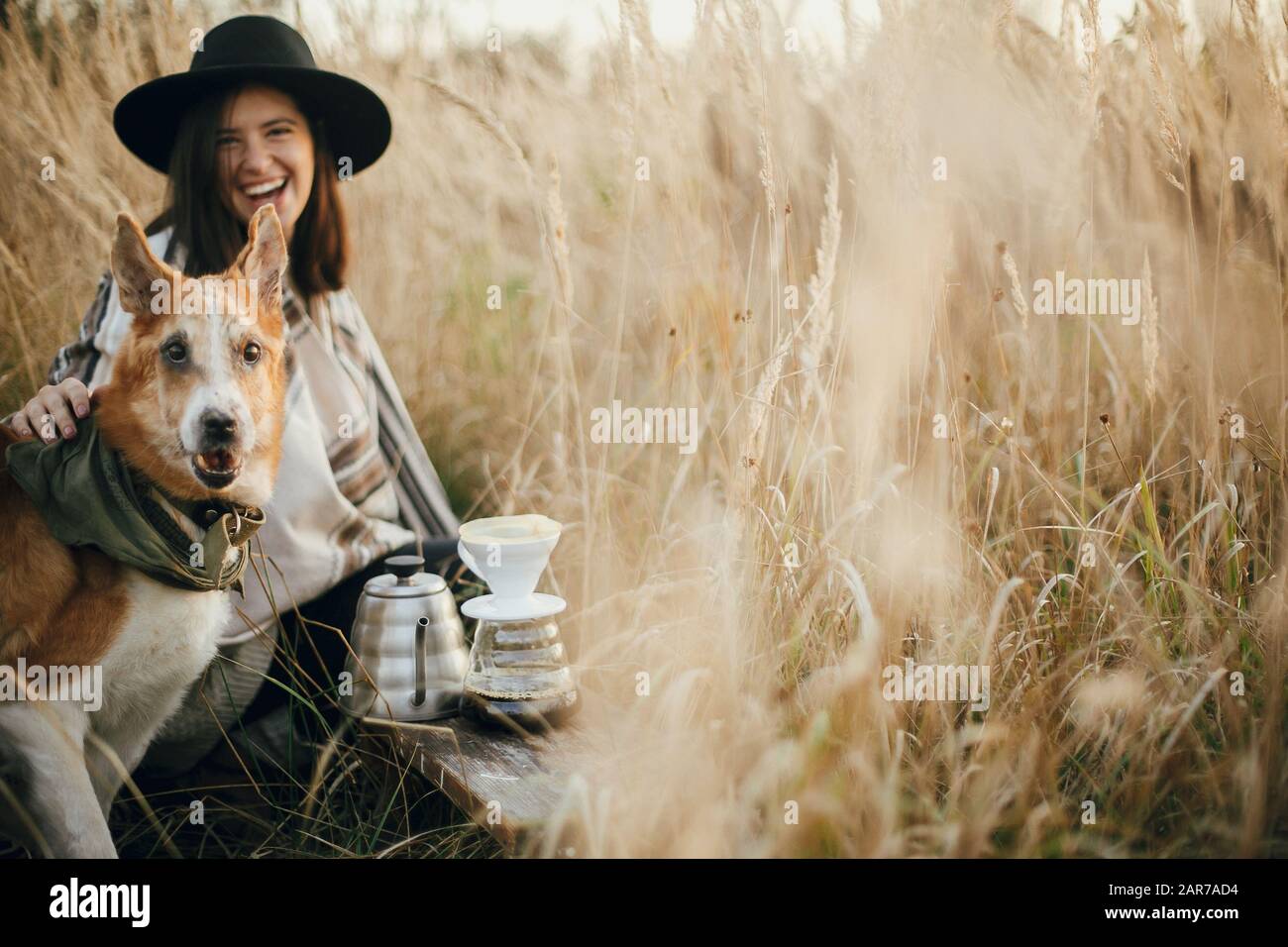 Stylish hipster traveler hugging her golden dog and smiling, brewing ...