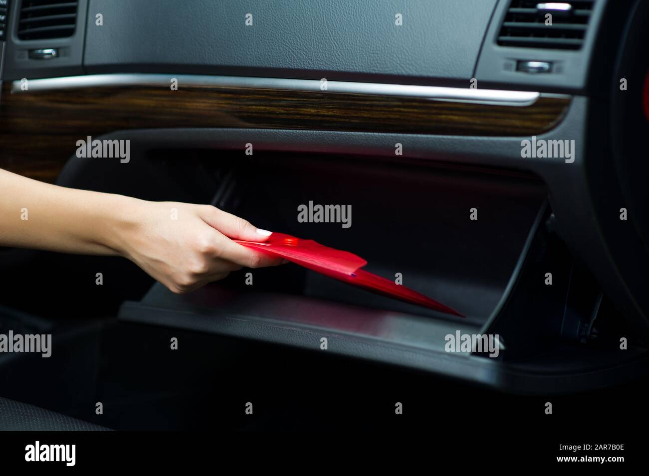 woman's hand takes a red folder from the glove box in the car Stock ...