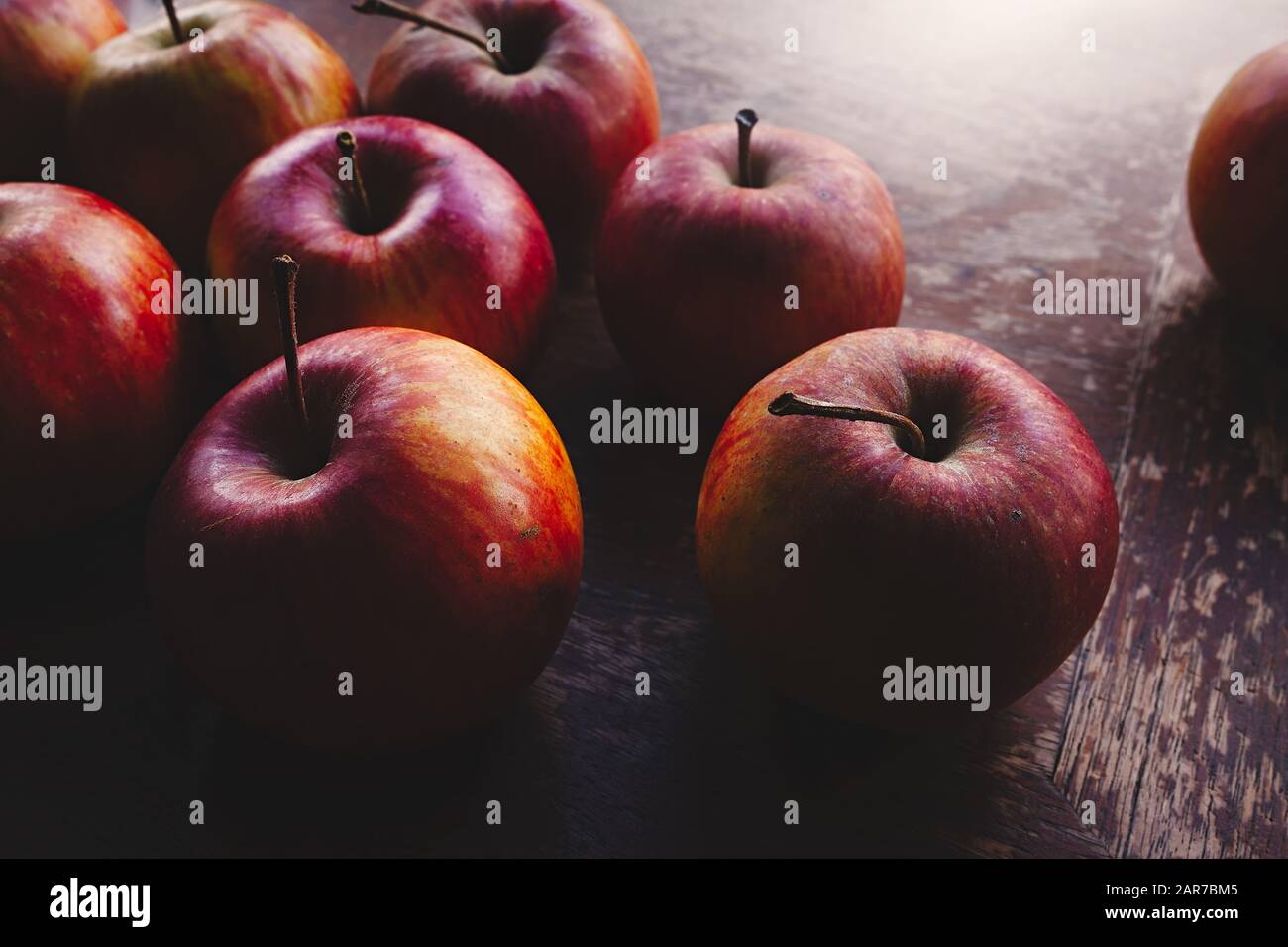 Organic grown, imperfect, fresh, shiny red apples on a table and light ...