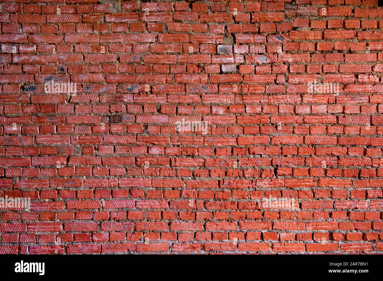 Red draft brick wall with interesting uneven lighting Stock Photo - Alamy