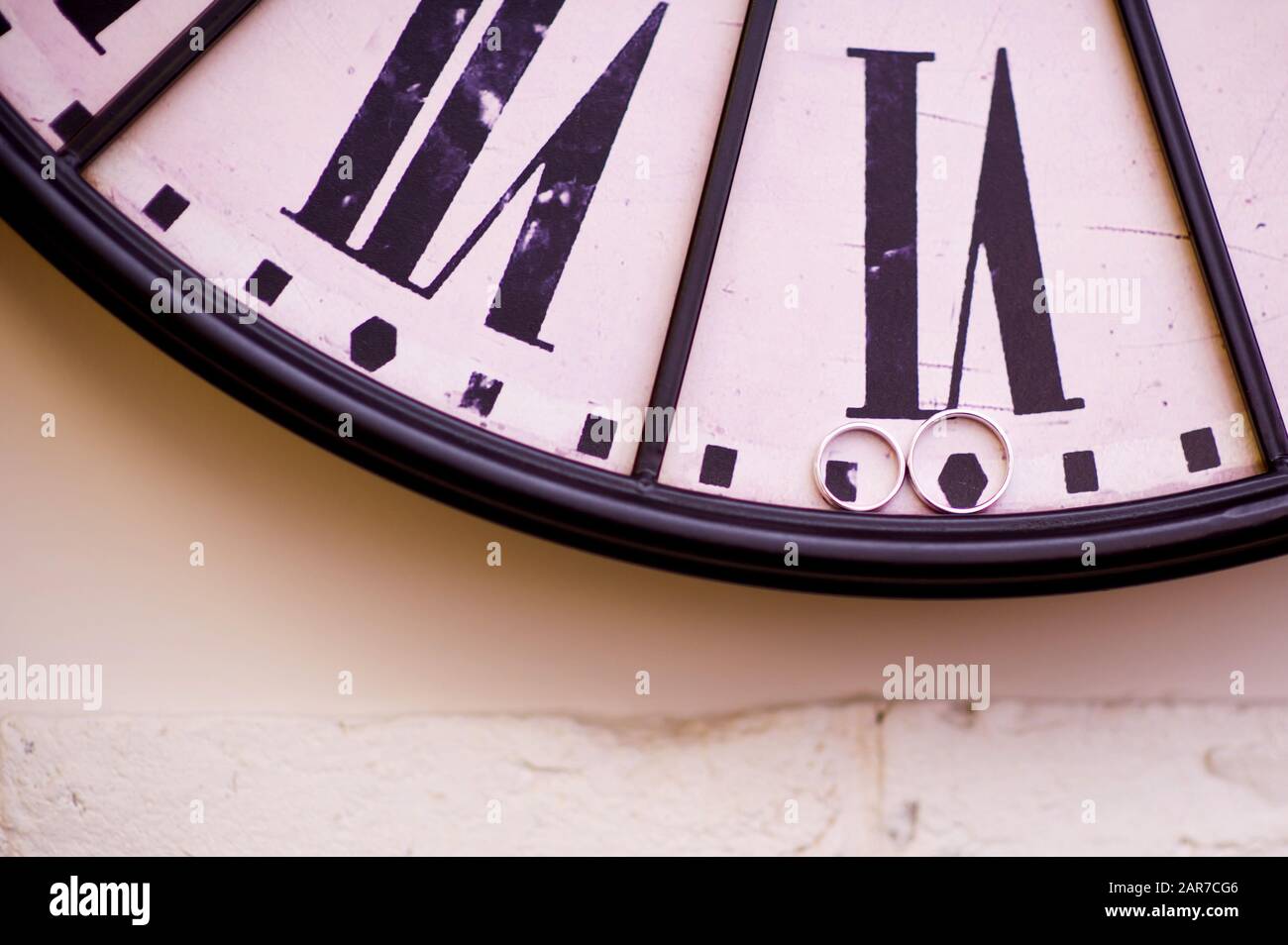 wedding rings lie on the dial of a wall clock Stock Photo - Alamy