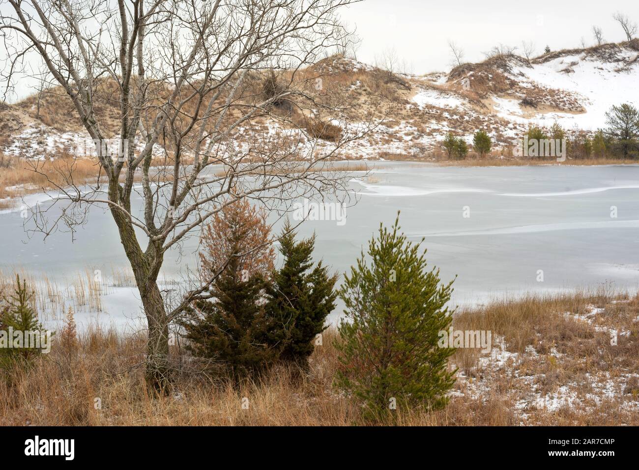 Snow covered dunes encircle a frozen lake in winter at the Indiana ...
