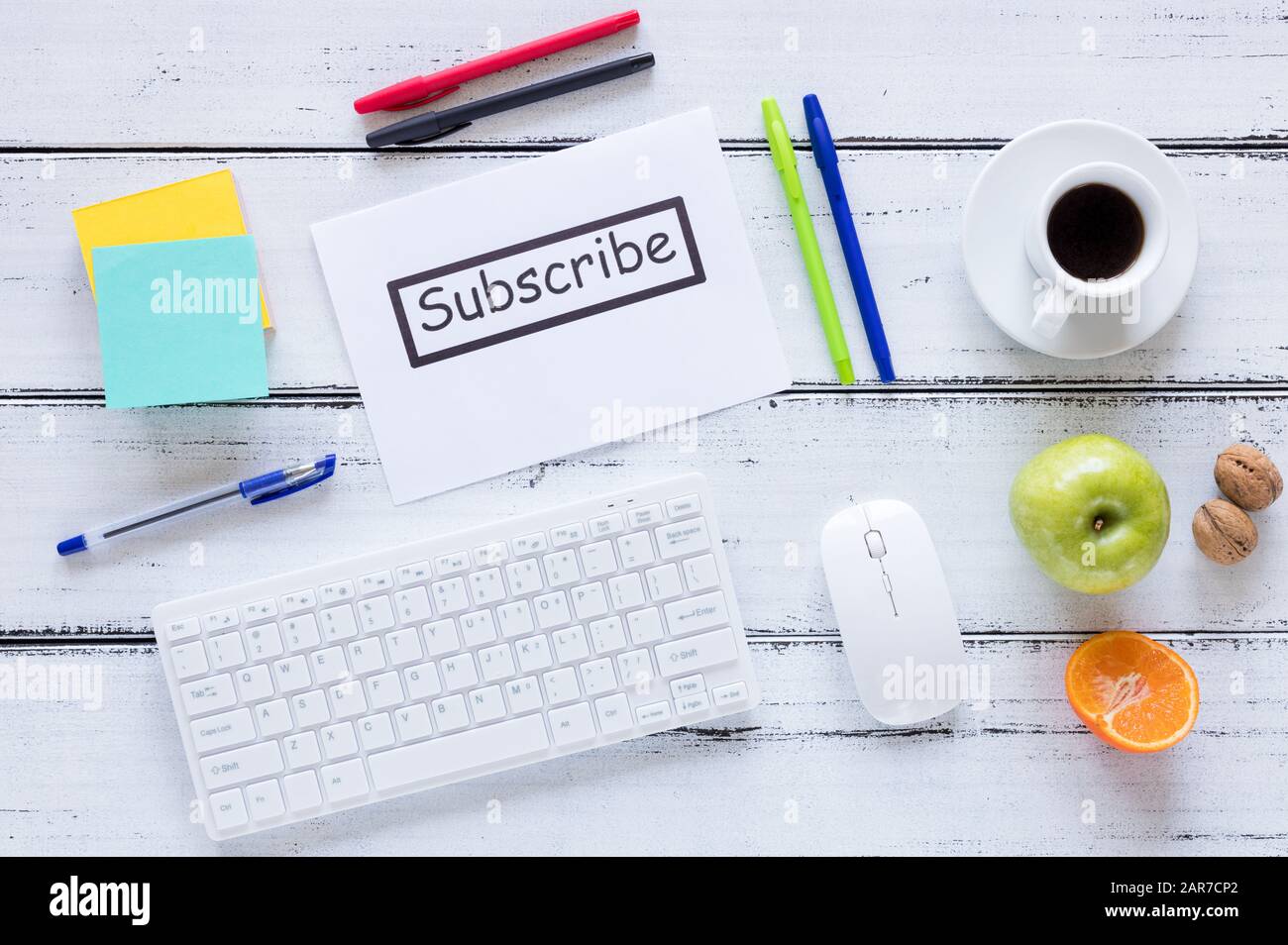a card with the words "subscribe" on a desk with a computer keyboard ...
