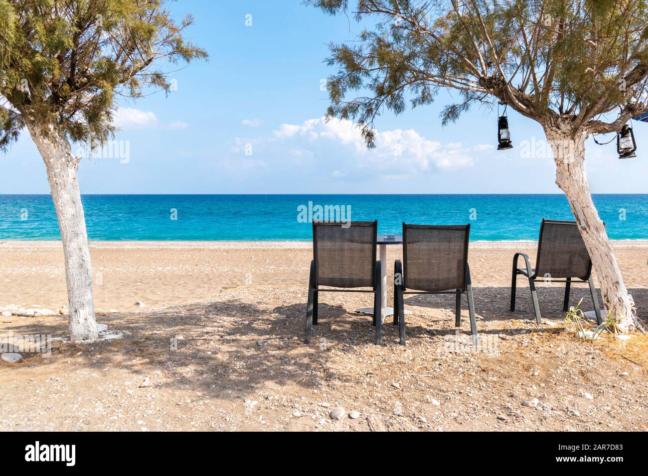 Empty chairs under tree with view of sea on Afandou beach near Faliraki ...