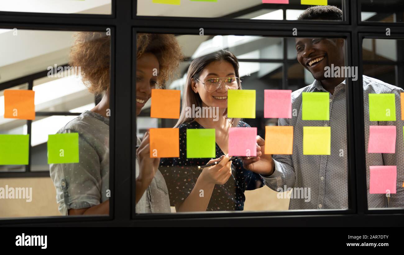 Smiling businesspeople using sticky notes during a brainstorming ...