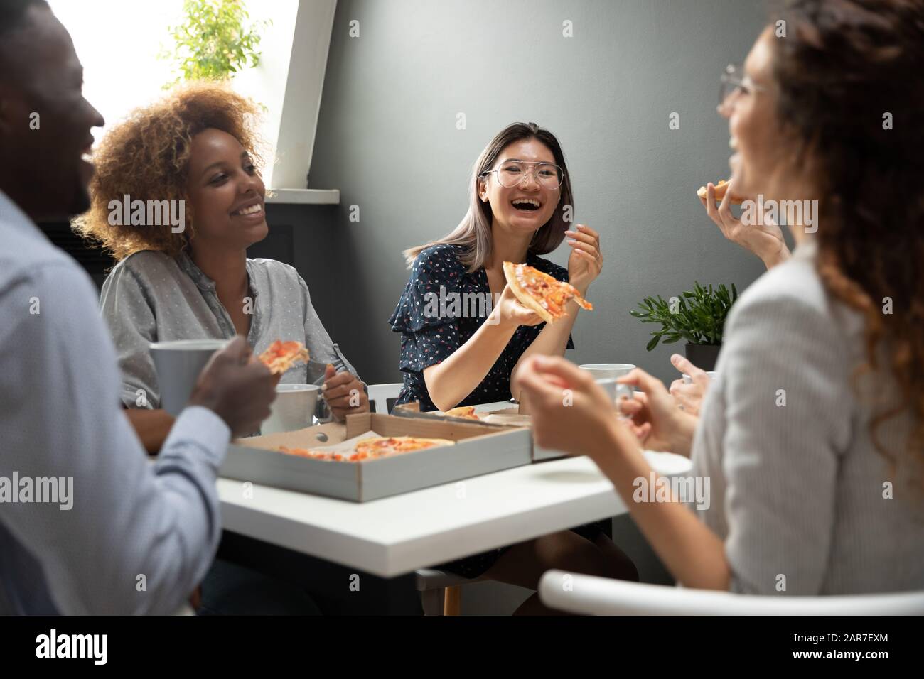 Smiling Multiethnic Colleagues Have Fun Eating Pizza In Office Stock