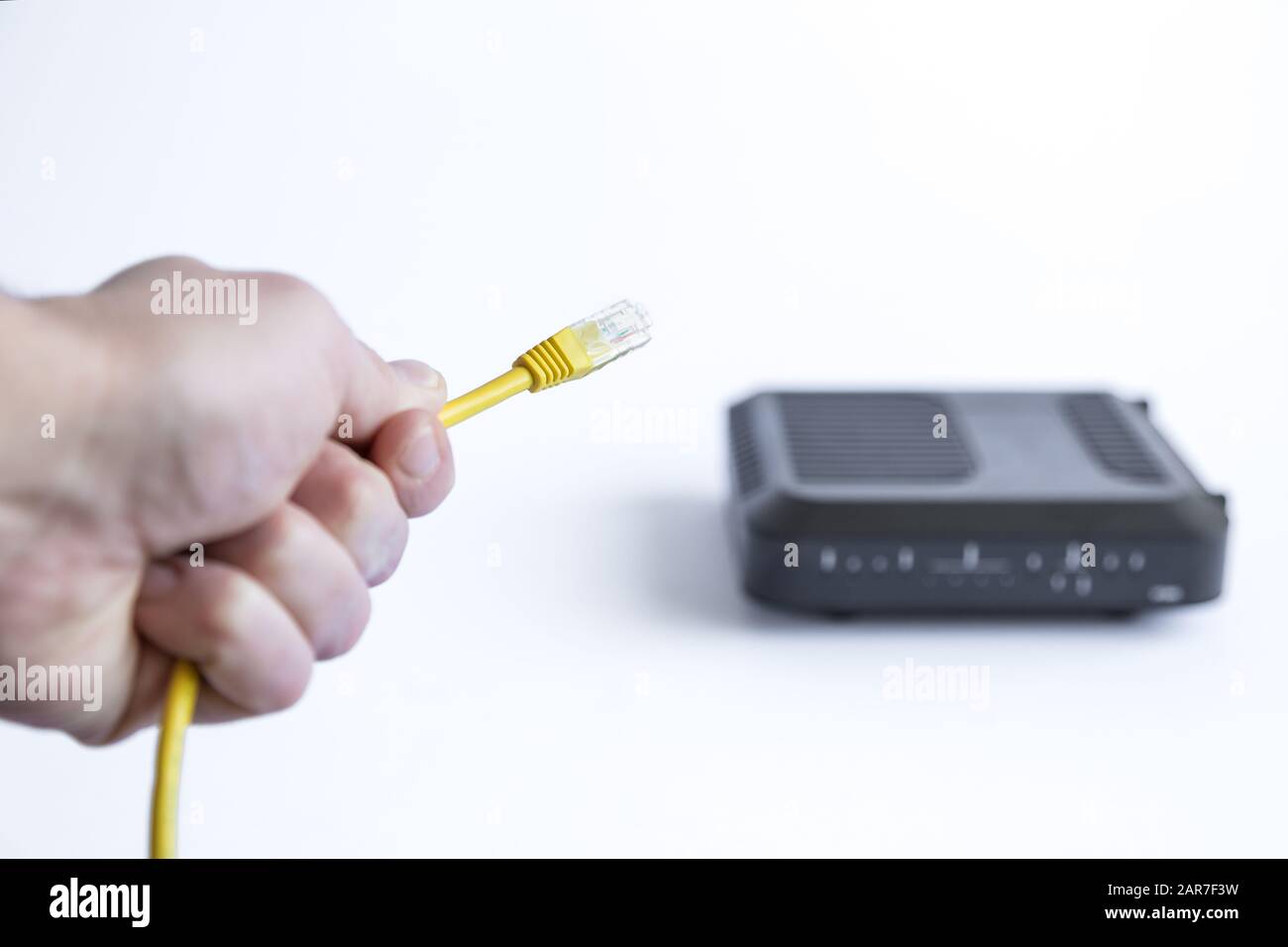 Man hand holding lan network cable with wireless router on white ...