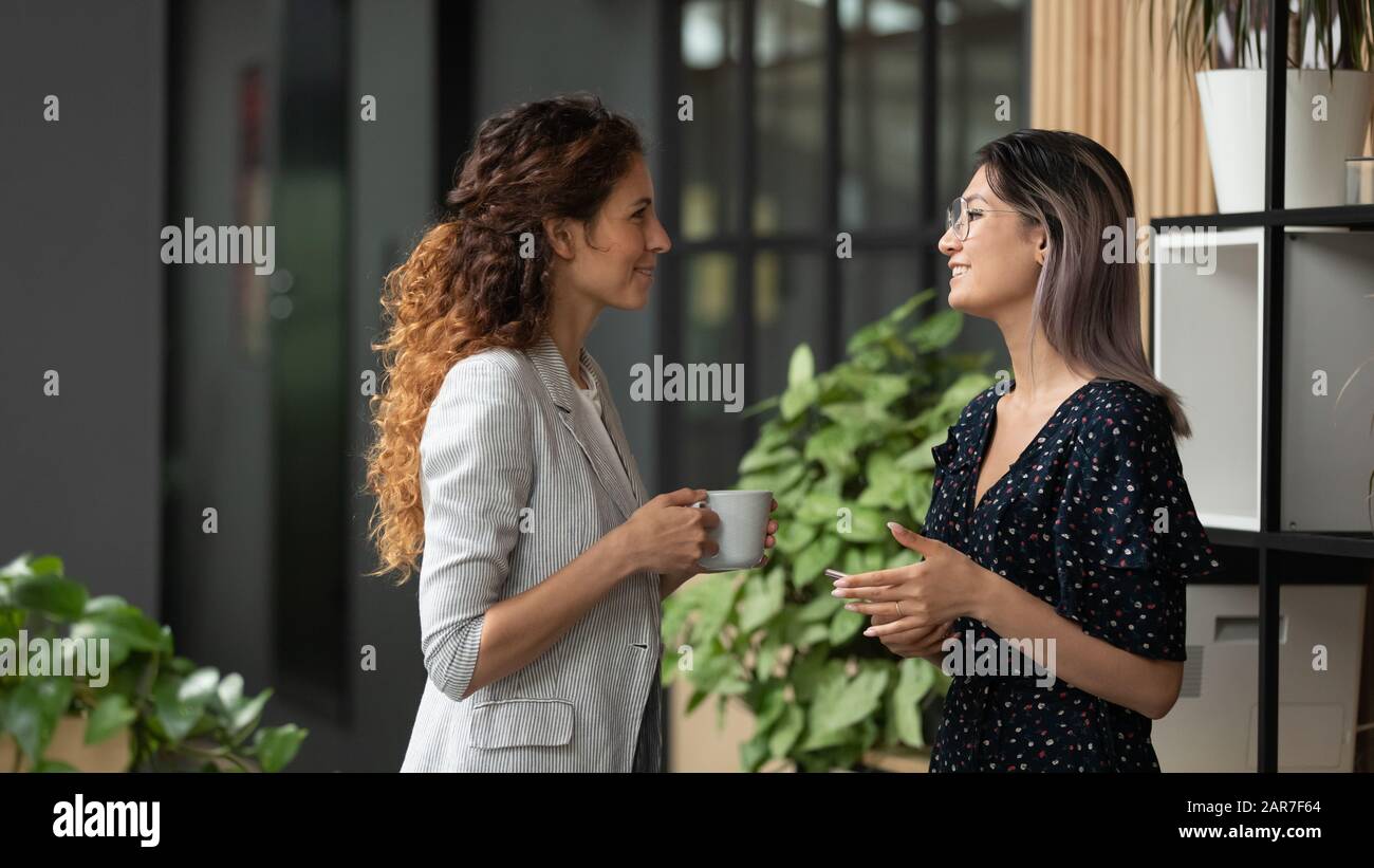 Multiethnic female colleagues chat during coffee break Stock Photo - Alamy