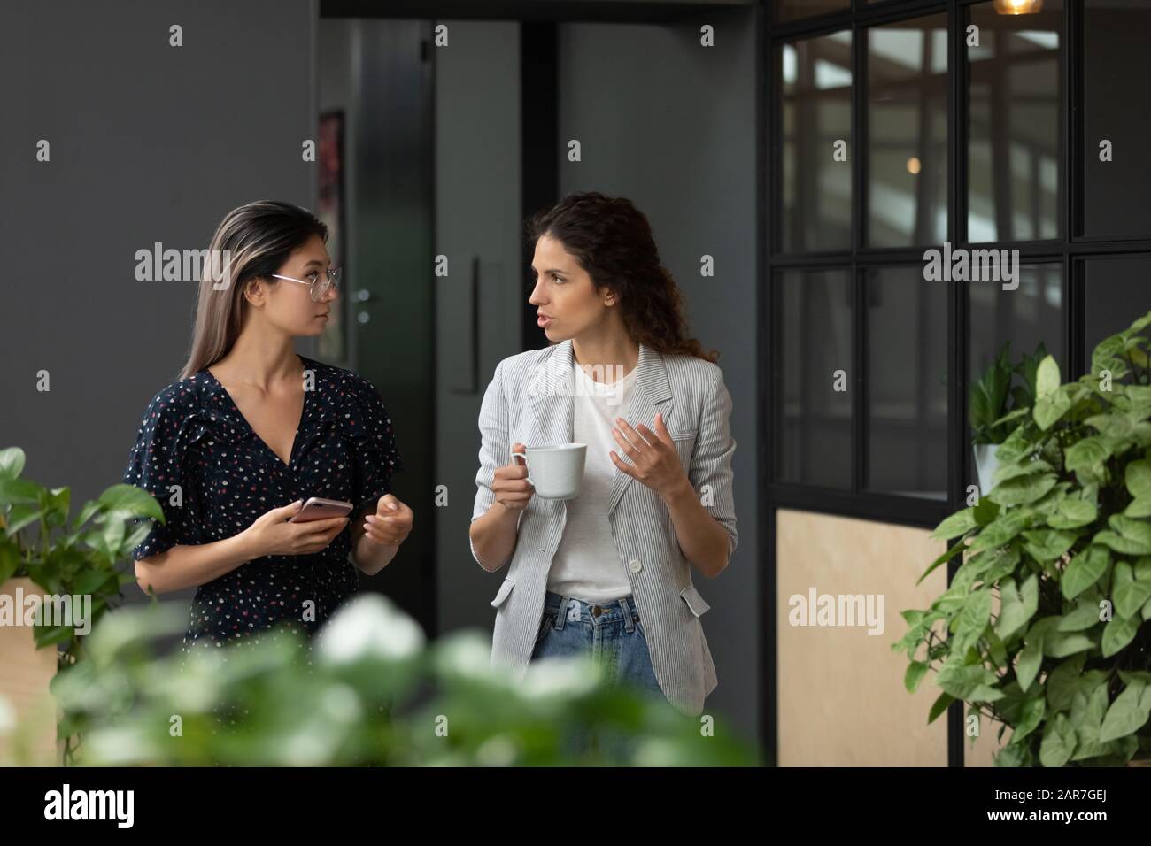 Millennial multiethnic female colleagues chat enjoying coffee break ...