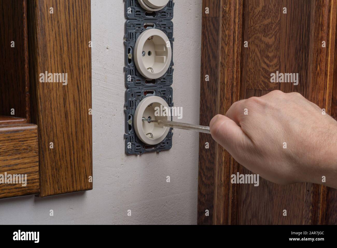 A master electrician mounts an electrical plug on a wall. Vintage ...