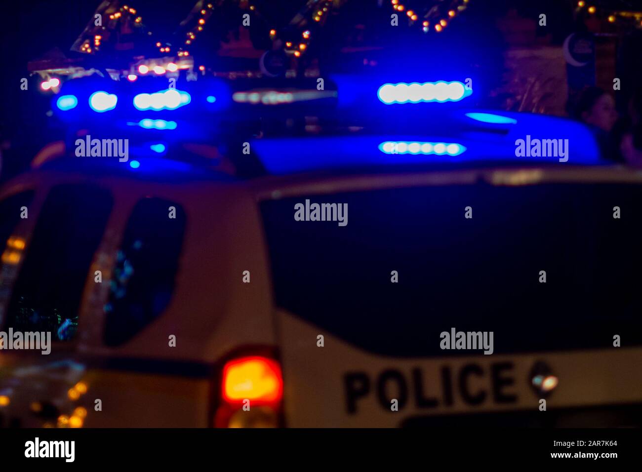Police car with flashing lights on at night among the lights of urban ...