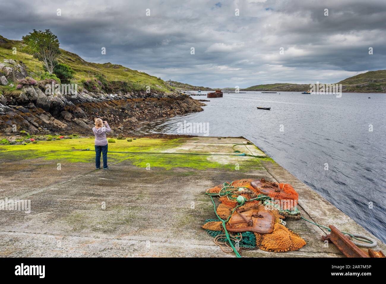 A female tourist taking photos on a mobile phone in the fishing village ...