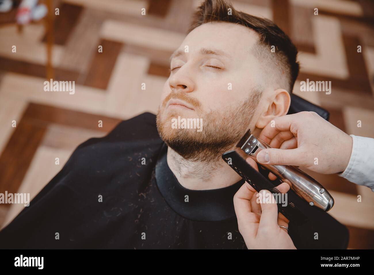 Close-up of barber shearing beard to man in barbershop electric razor ...