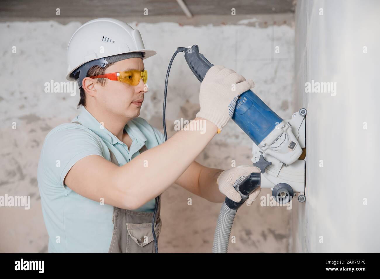 Builder worker cutting electrical chase in concrete wall with ...