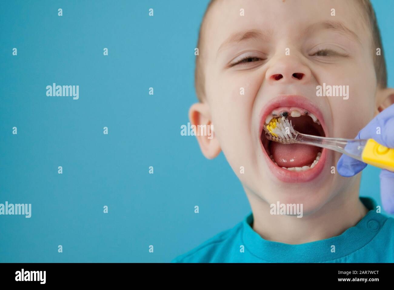 Little cute boy brushing his teeth on blue background Stock Photo - Alamy