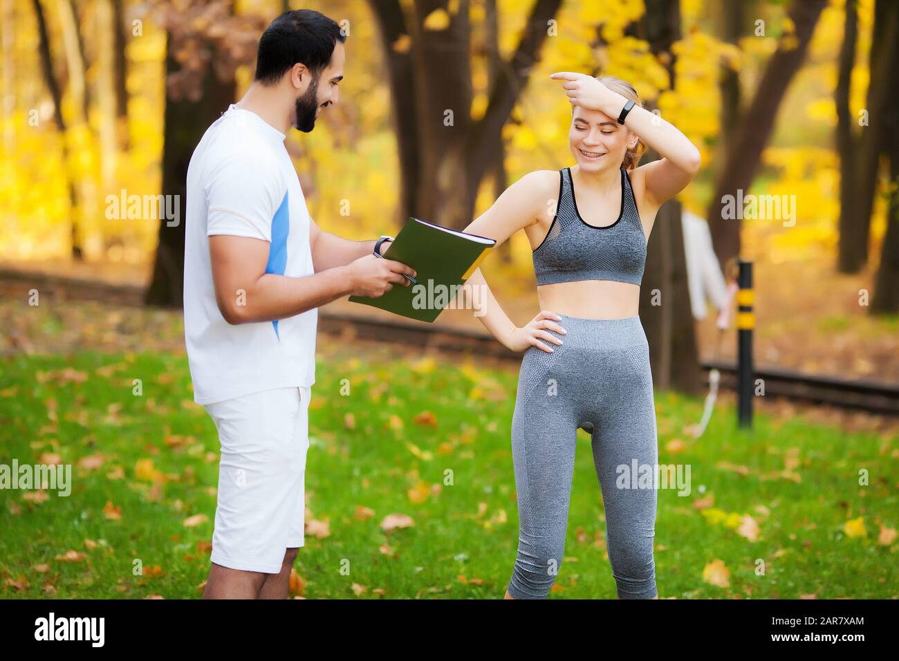 Fitness. Personal Trainer Takes Notes While Woman Exercising Outdoor ...