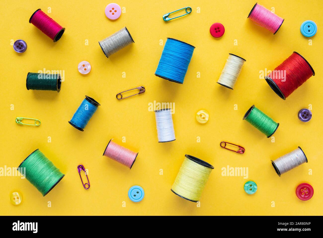 Flat lay with spools of colored thread, buttons and safety pins on ...