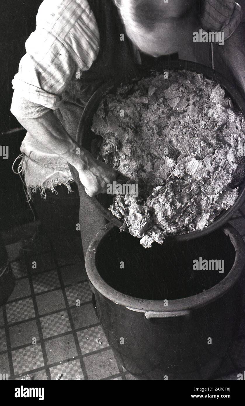 1950s, historical, making mead, a man putting chunks of natural honey ...