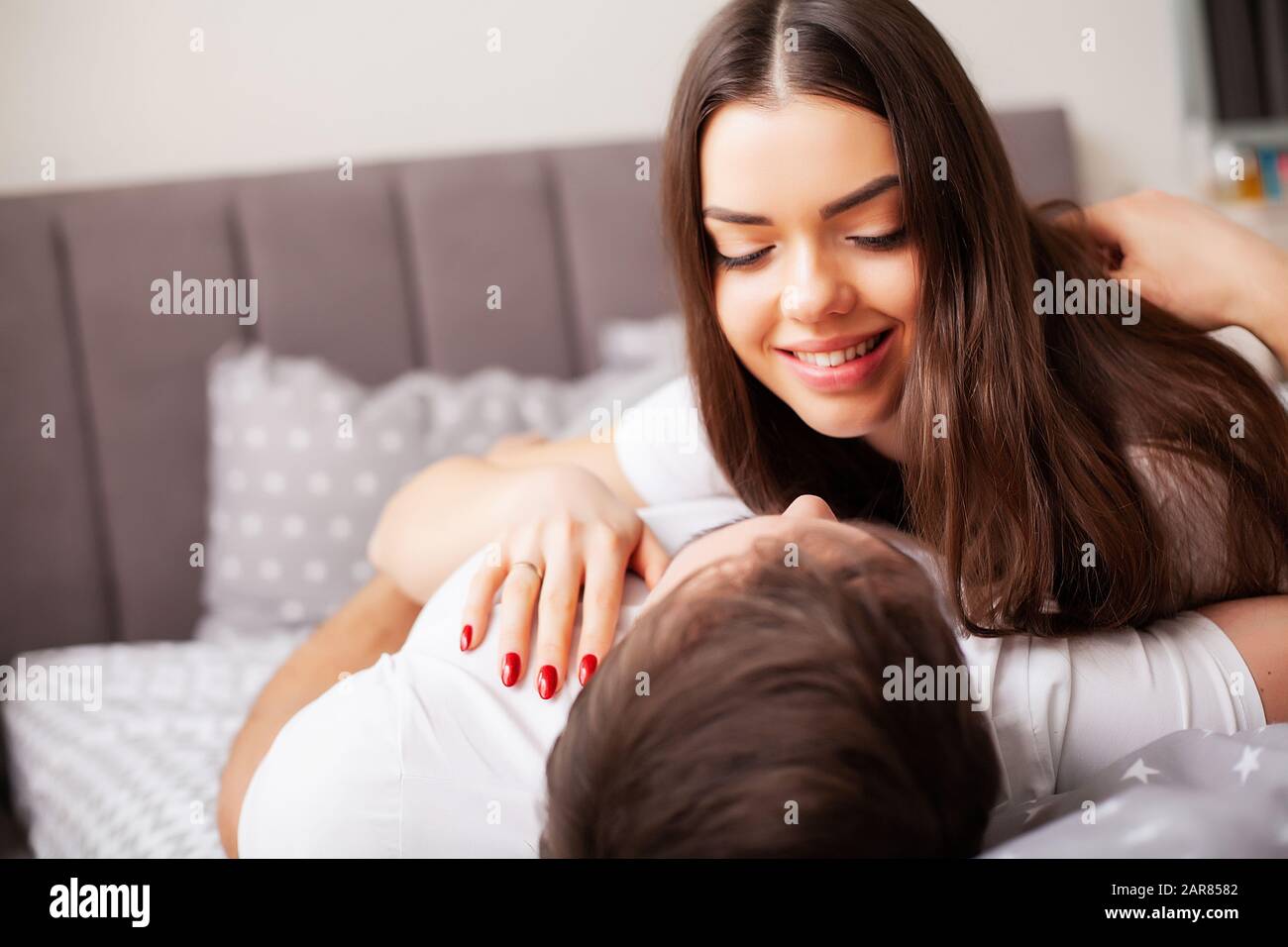 Happy couple having fun in bed. Intimate sensual young couple in bedroom enjoying each other ...