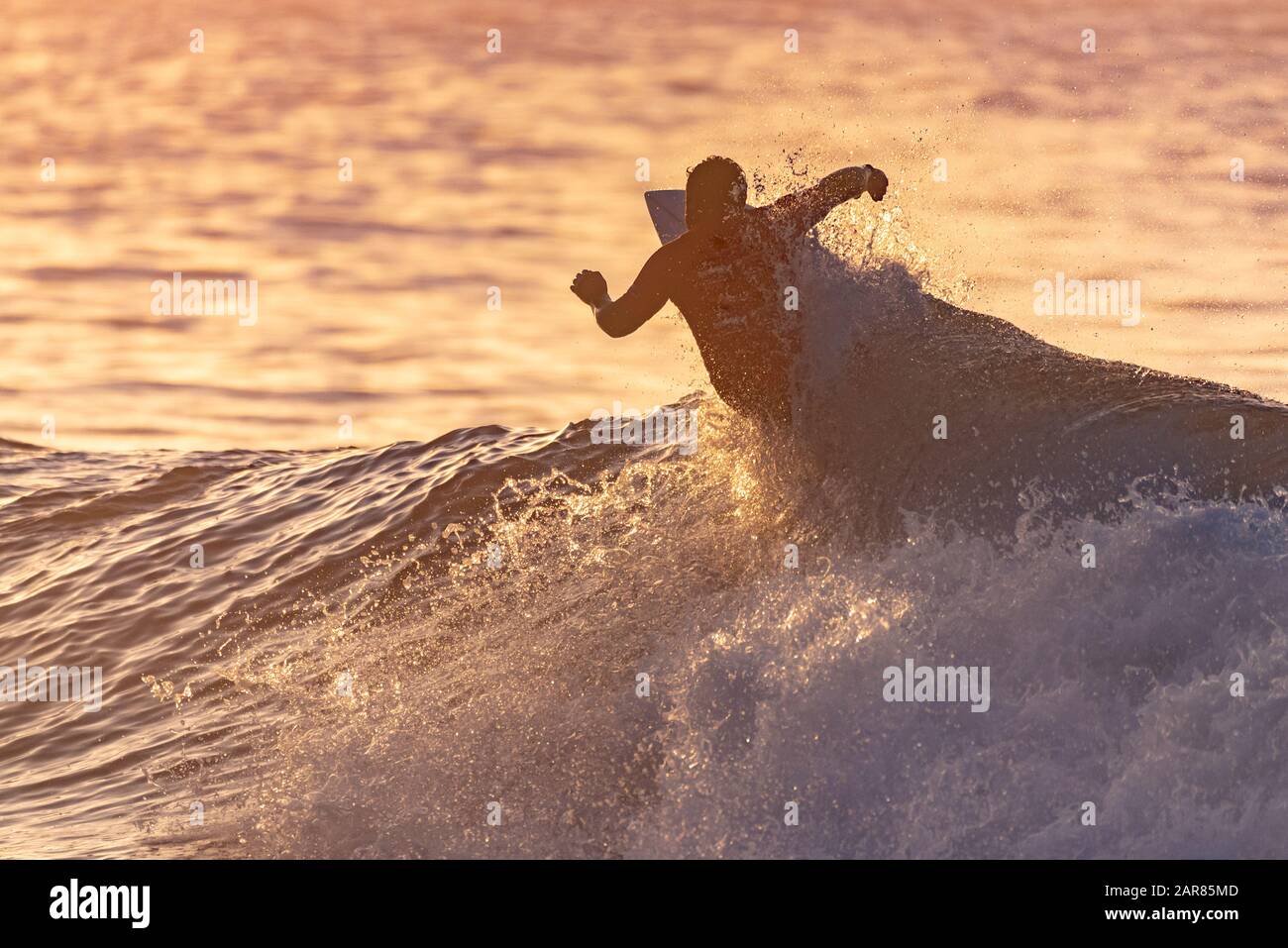 Surfer contestant in contest jersey is silhouetted against the ...