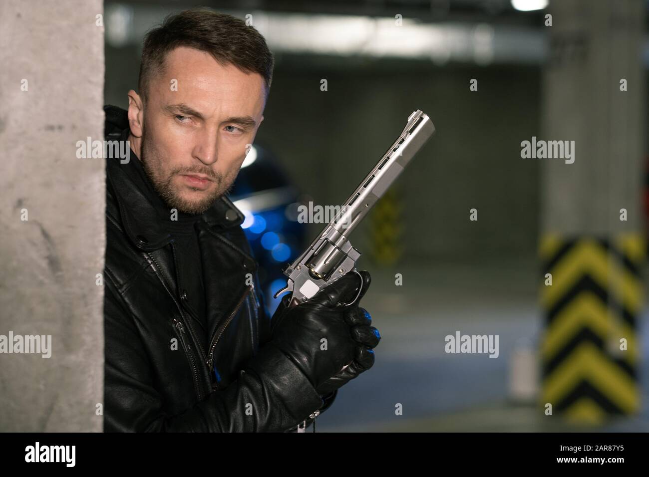 Young killer or agent holding gun and getting ready to shoot victim or ...