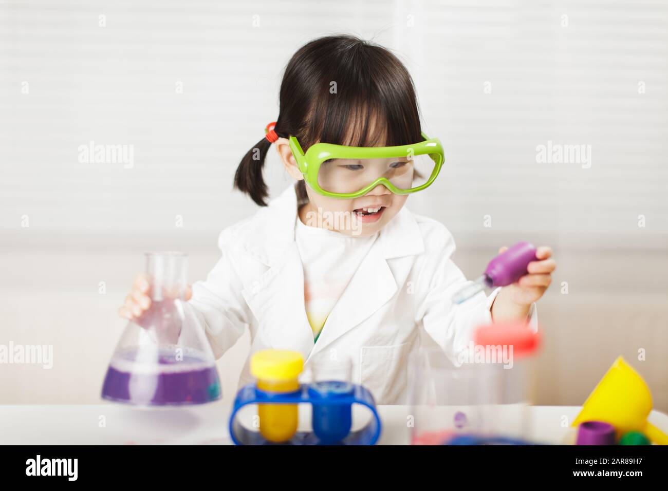toddler girl pretend play scientist role at home against white ...