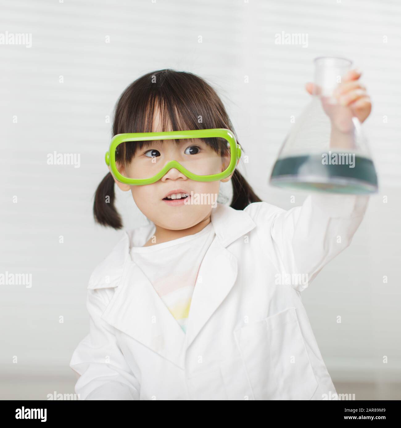 toddler girl pretend play scientist role at home against white ...