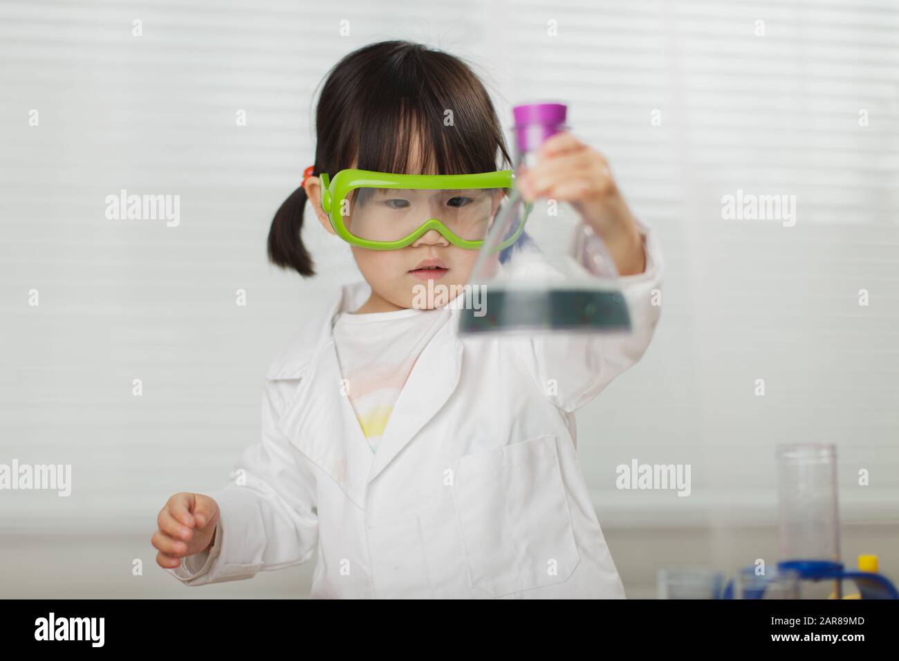 toddler girl pretend play scientist role at home against white ...