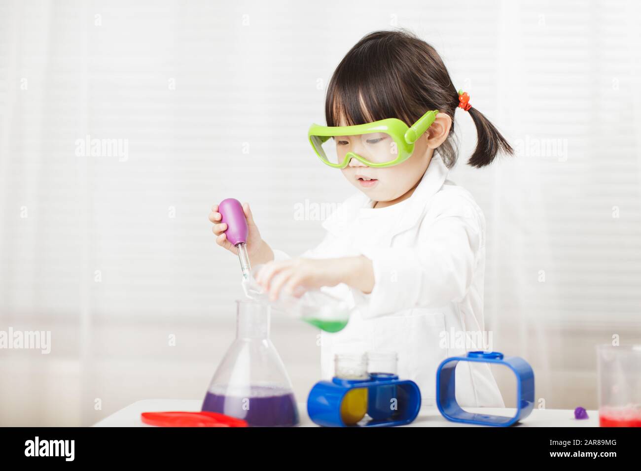 toddler girl pretend play scientist role at home against white ...
